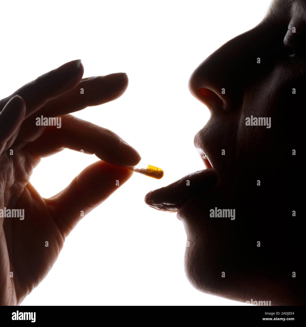Taking pill. Woman placing a pill in her mouth Stock Photo - Alamy