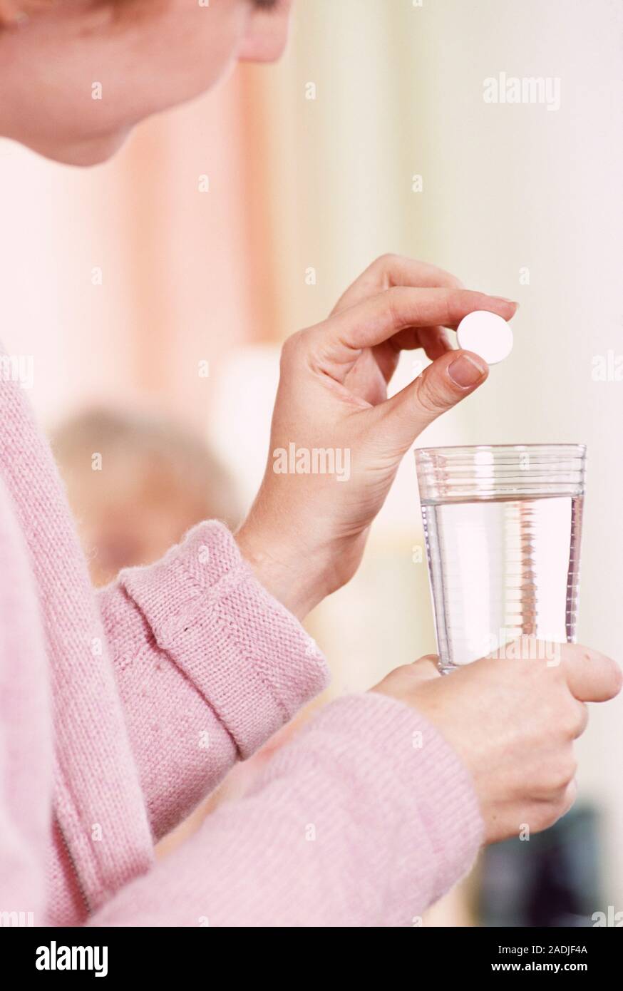Taking aspirin. Woman placing a tablet of the painkilling (analgesic ...