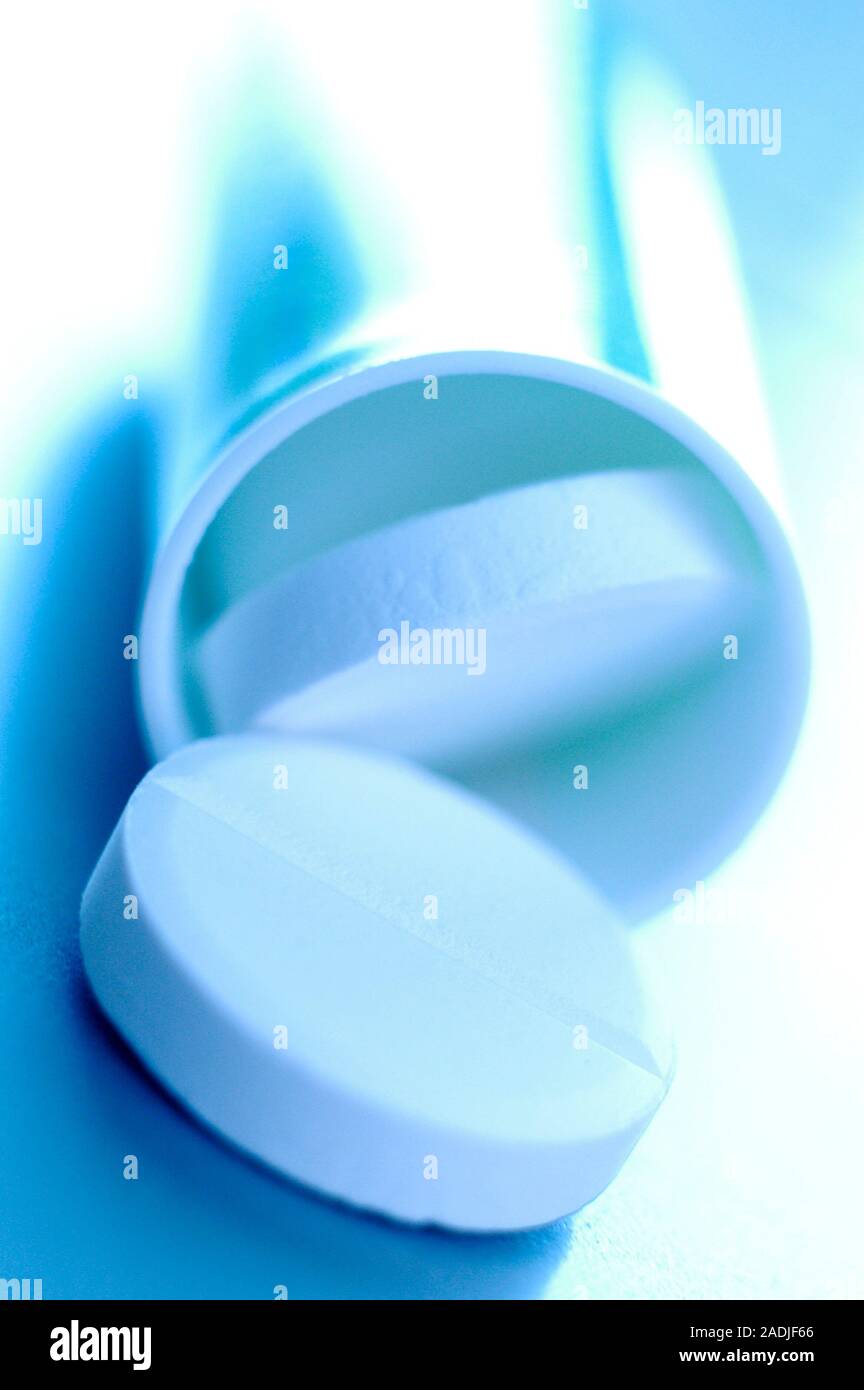 Aspirin tablets falling out of a tube. Aspirin (acetylsalicylic acid ...