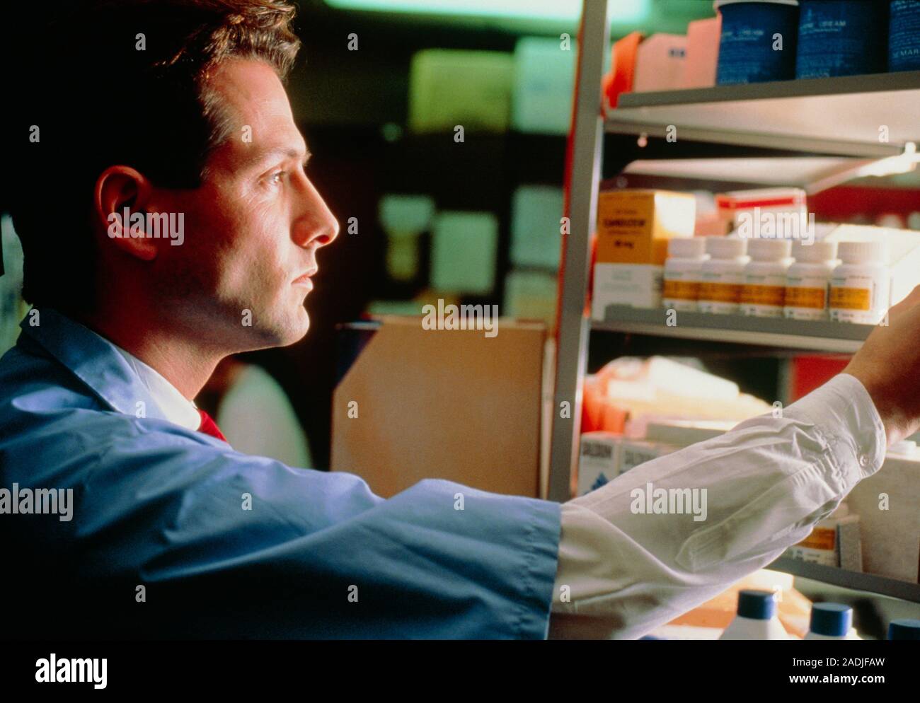 Pharmacist at work. A male pharmacist (druggist) dispenses a drug from ...
