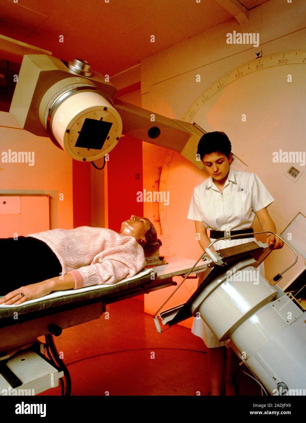 Radiotherapy: a radiographer (standing) adjusts the positioning of the ...