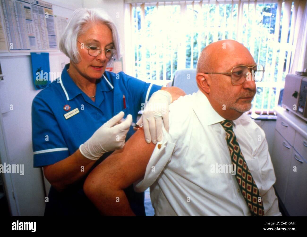 Injection. Nurse using a syringe to inject a patient with a drug or ...