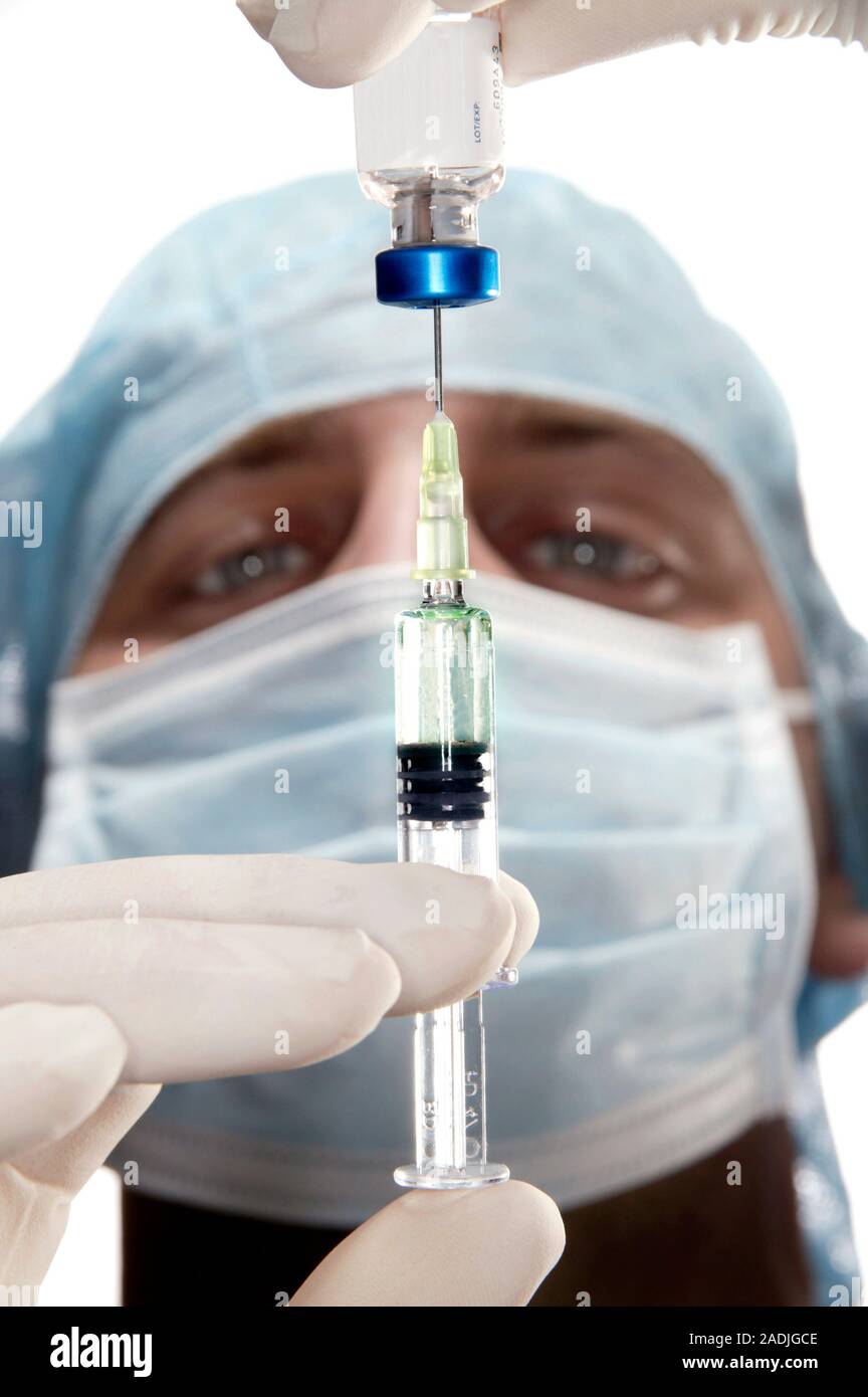 Preparing an injection. Doctor in sterile clothing drawing a drug into ...