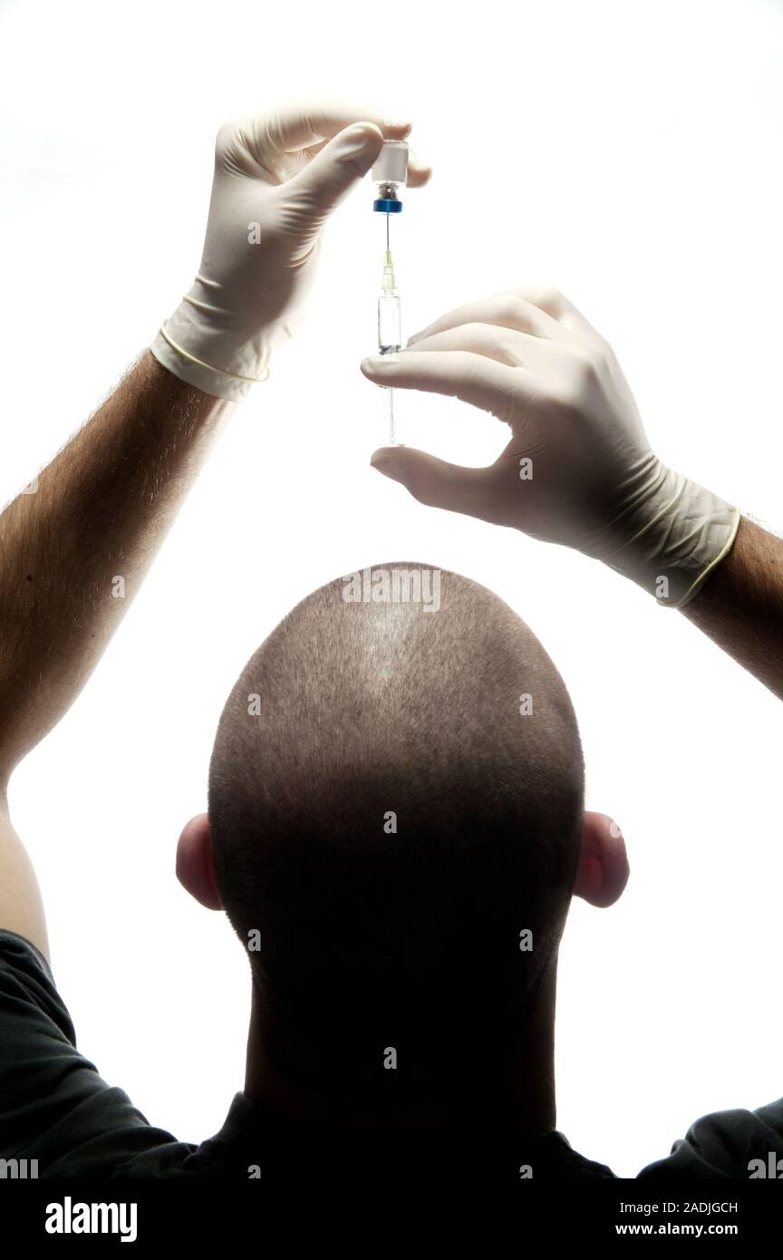 Preparing an injection. Doctor in sterile clothing drawing a drug into ...