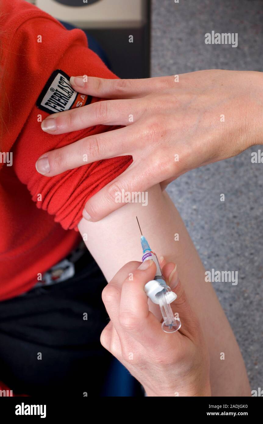 Hepatitis A and typhoid vaccination. Teenage girl's arm being injected ...