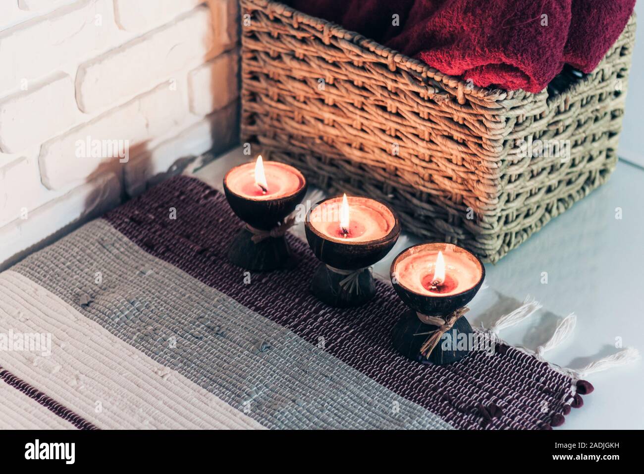 Burning spa aroma candle in coconut shell on a knitted multicolored rug ...