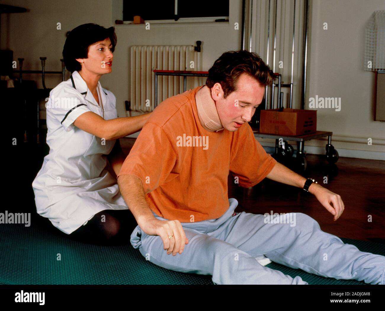 Physiotherapist assisting a young man suffering from paralysis in all ...