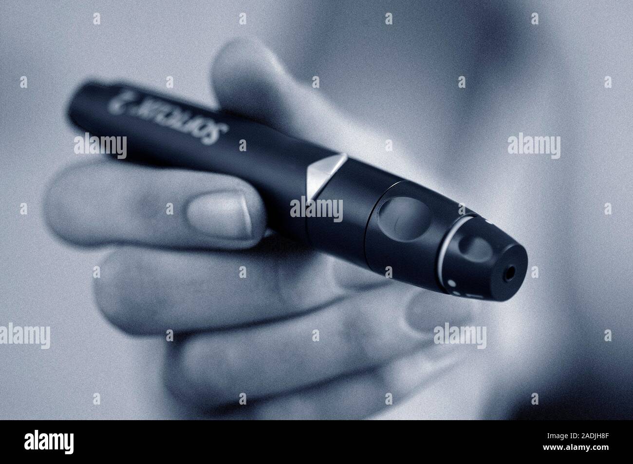 Diabetic blood sampler. Hand holding a device used to obtain blood ...