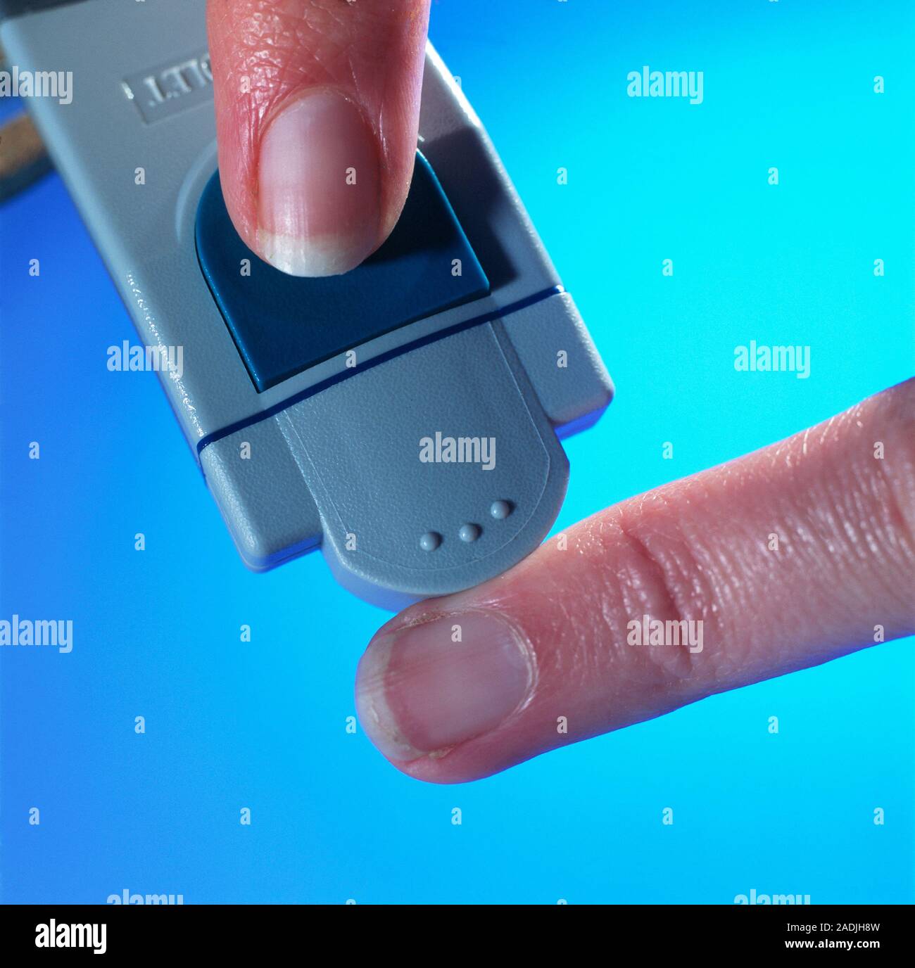 Blood sugar level testing. Lancet being used to obtain a drop of blood ...