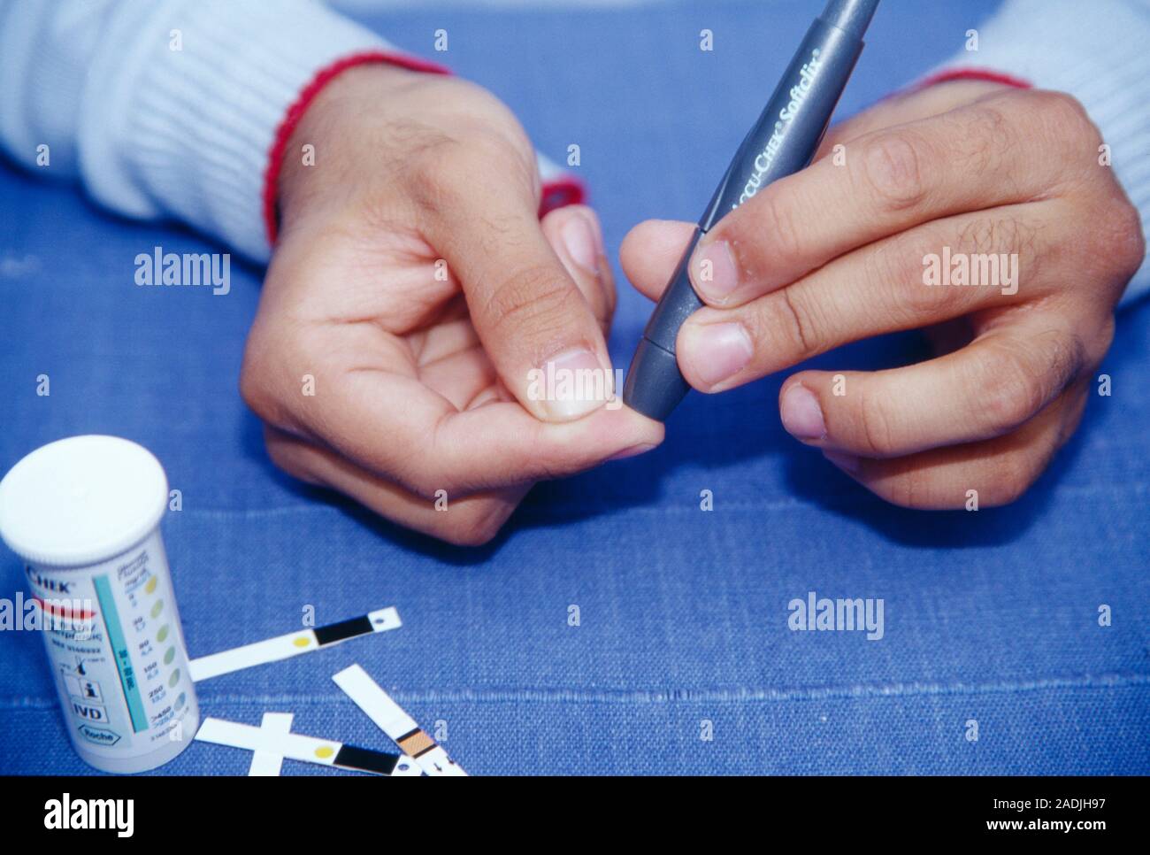Blood glucose test. Hands of a patient using a pen-like lancing device ...