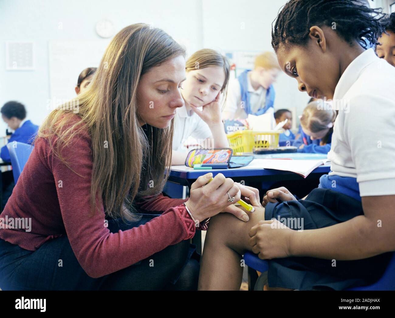 Insulin injection. Teacher helping a diabetic schoolgirl to inject ...