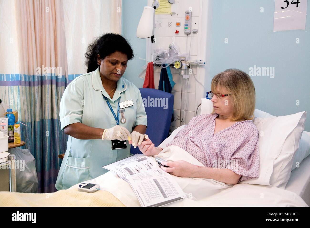 MODEL RELEASED. Blood glucose test. Nurse pricking a diabetic patient's ...