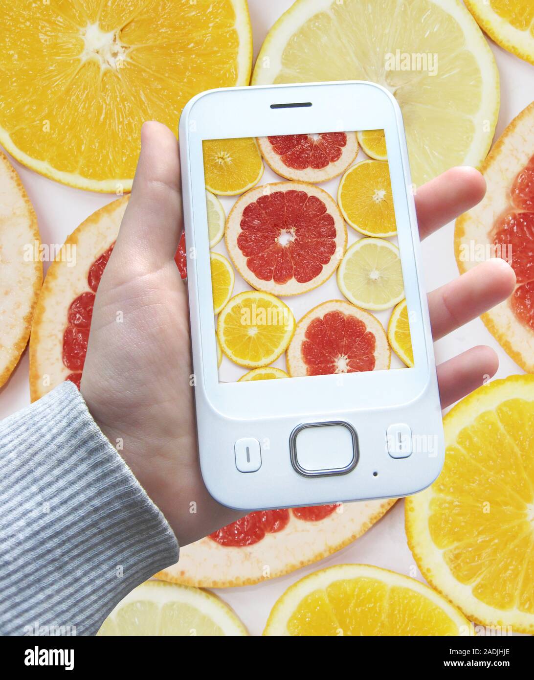 Modern smartphone with image of citrus fruits on screen in hand ...