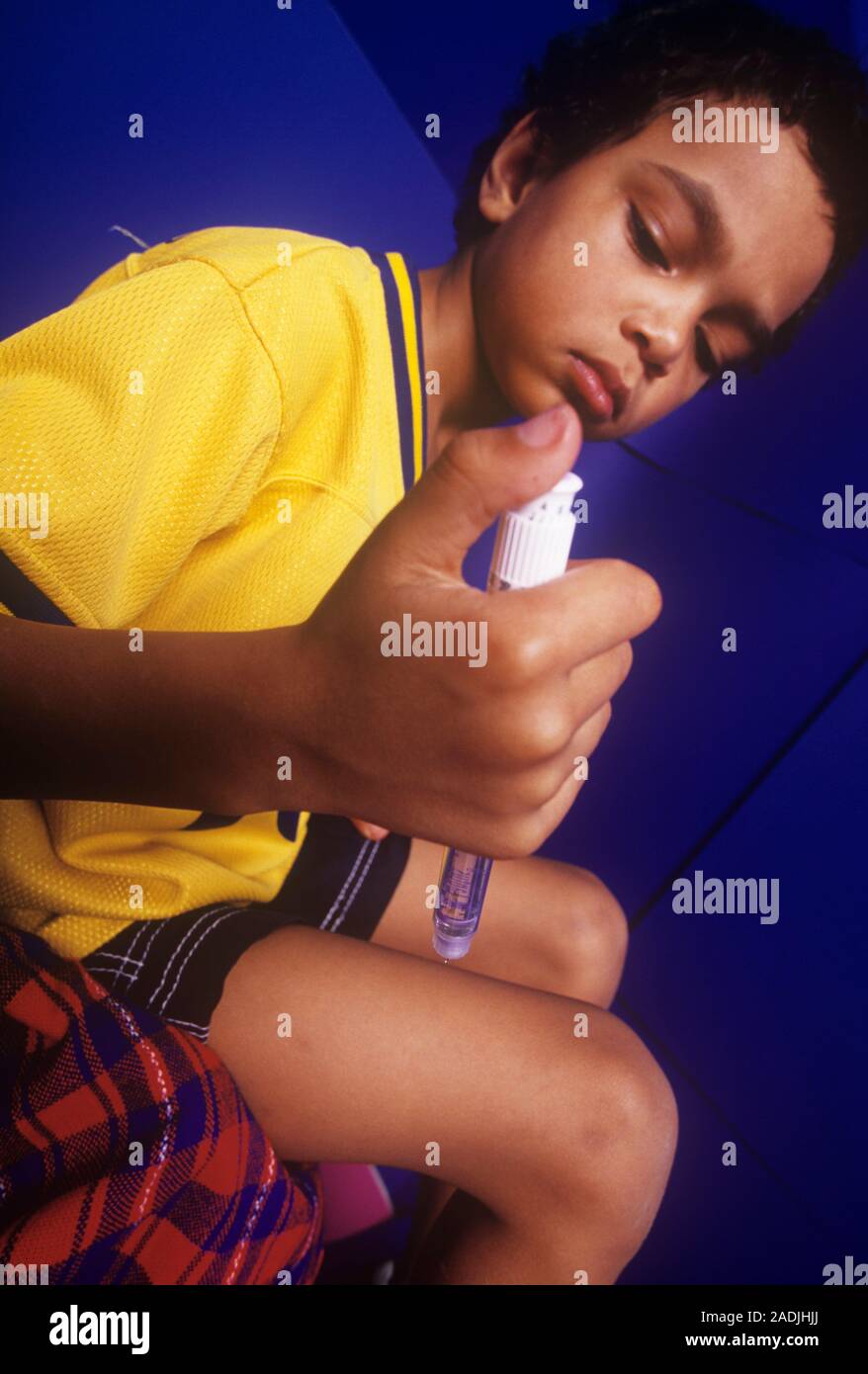 Insulin injection. Diabetic boy using an insulin pen to inject a dose ...