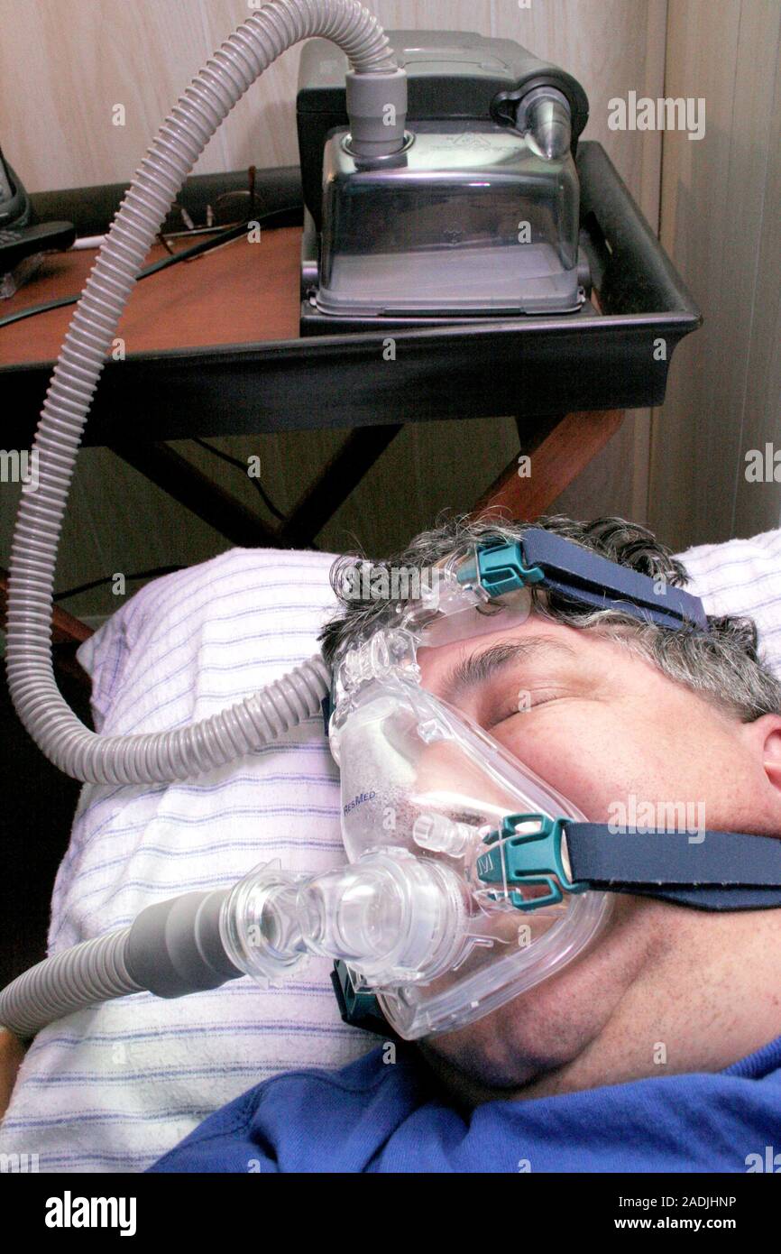 Sleep apnoea treatment. Middle- aged man using a continuous positive ...