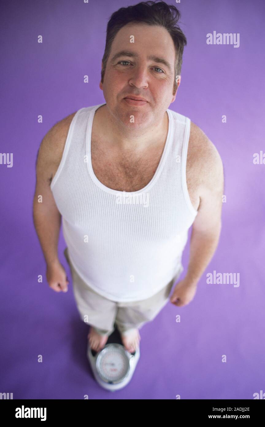 Weight watching. 39-year-old overweight man weighing himself on a set ...