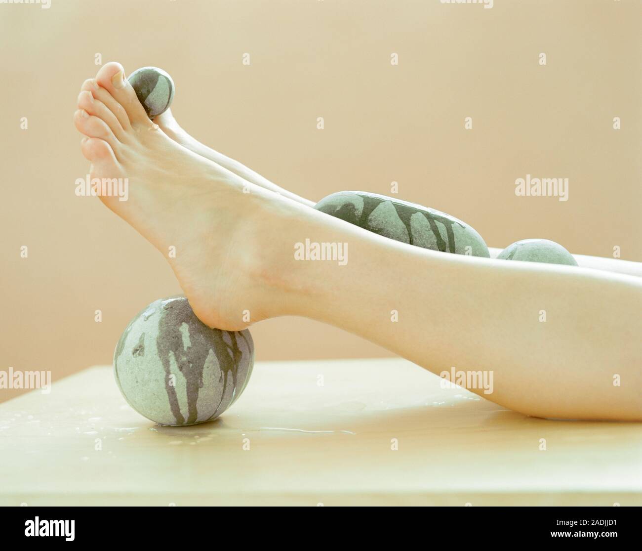 Stone therapy for legs and feet. The stones are heated and placed on ...