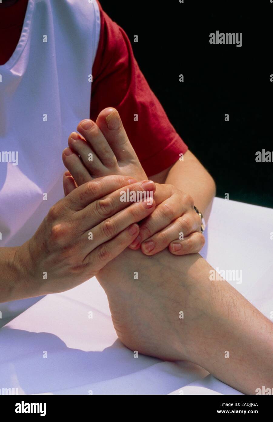 Reflexologist at work on a man's left foot. Reflexology (reflex zone ...