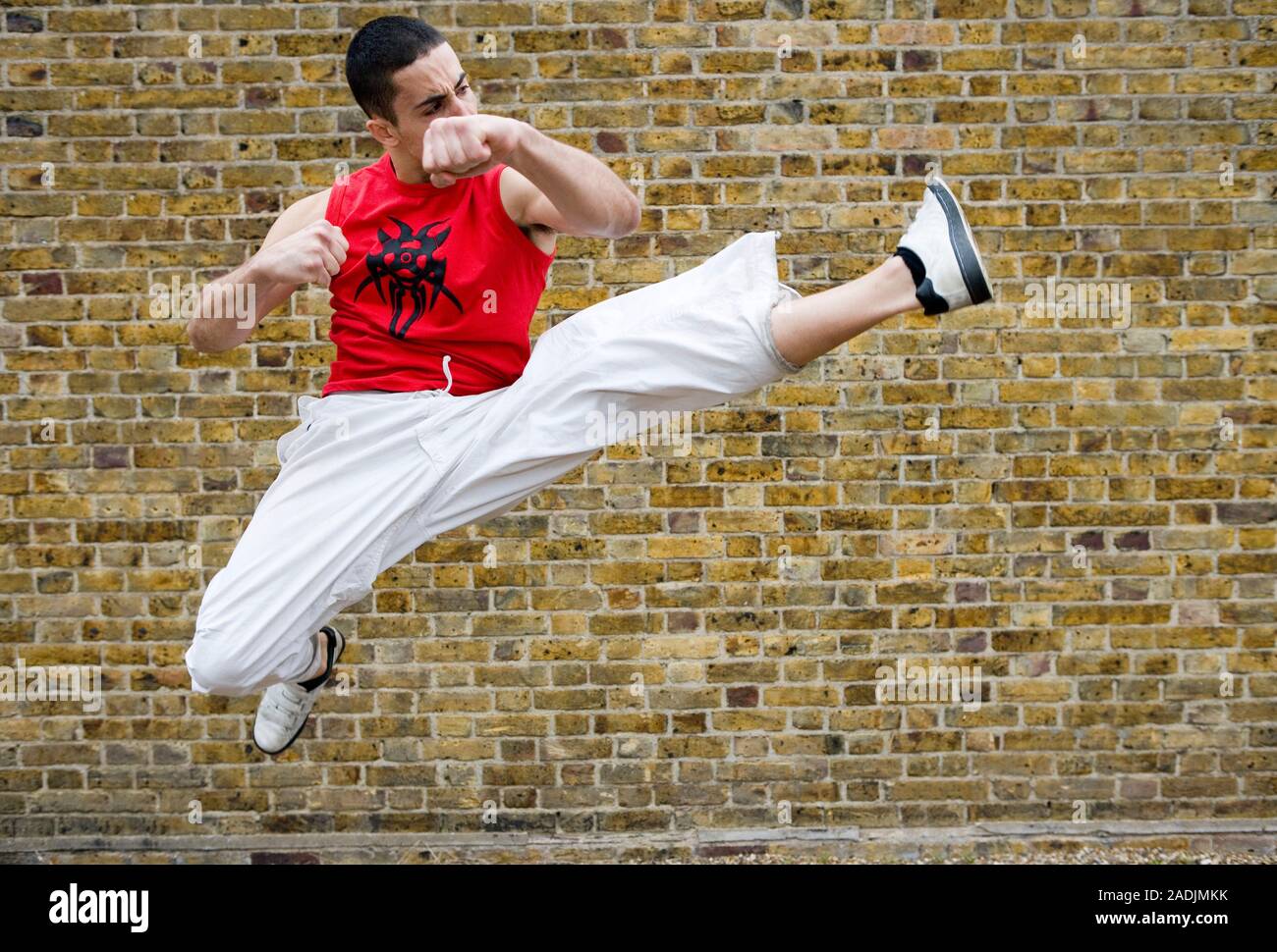MODEL RELEASED. Martial arts kick. Man performing a jumping kick ...