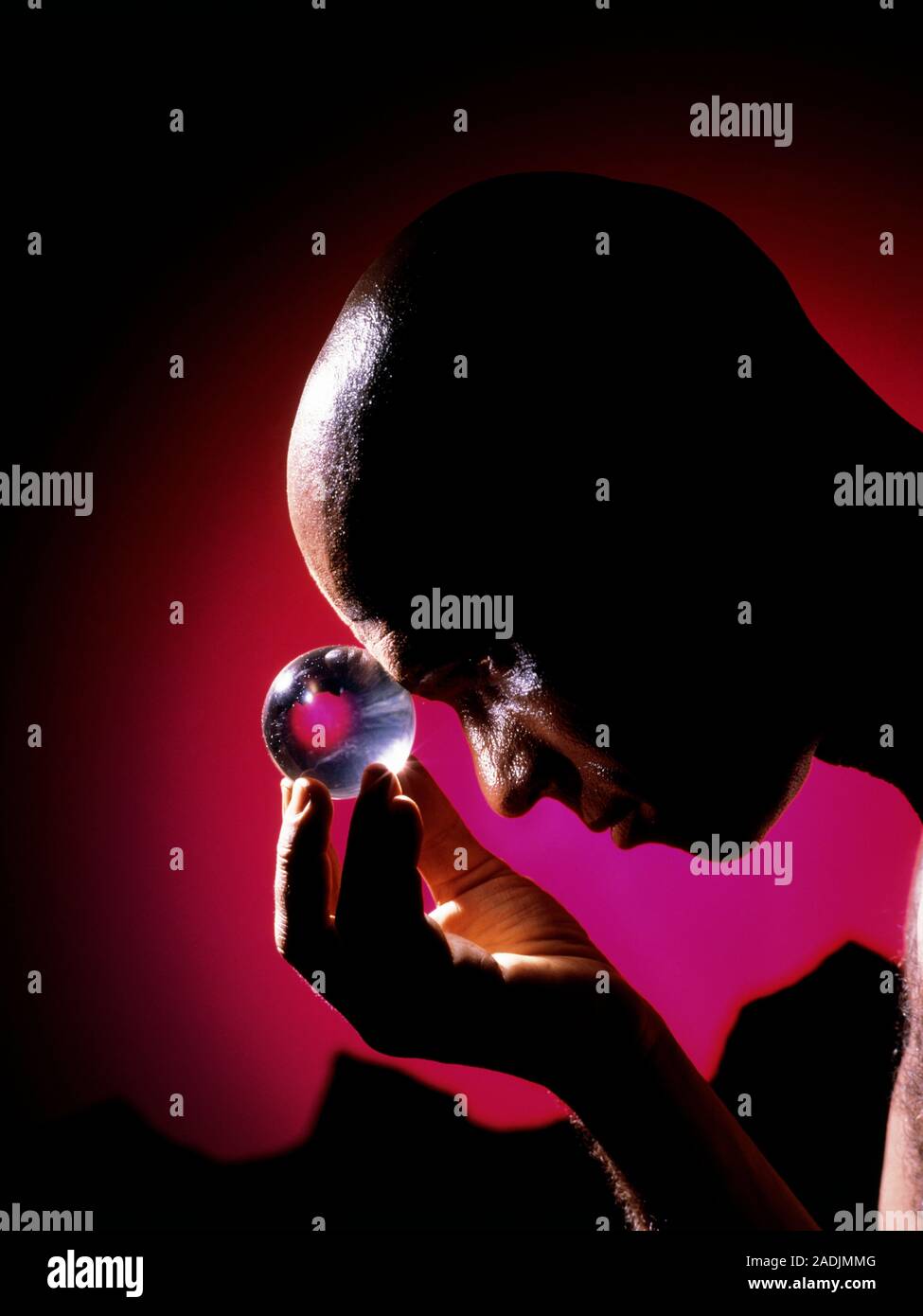 Crystal ball gazing. Man gazing into a crystal ball held at his ...