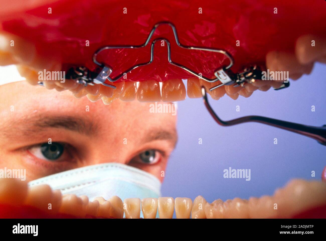 Dental check-up. Face of a dentist seen from inside a model mouth as he ...