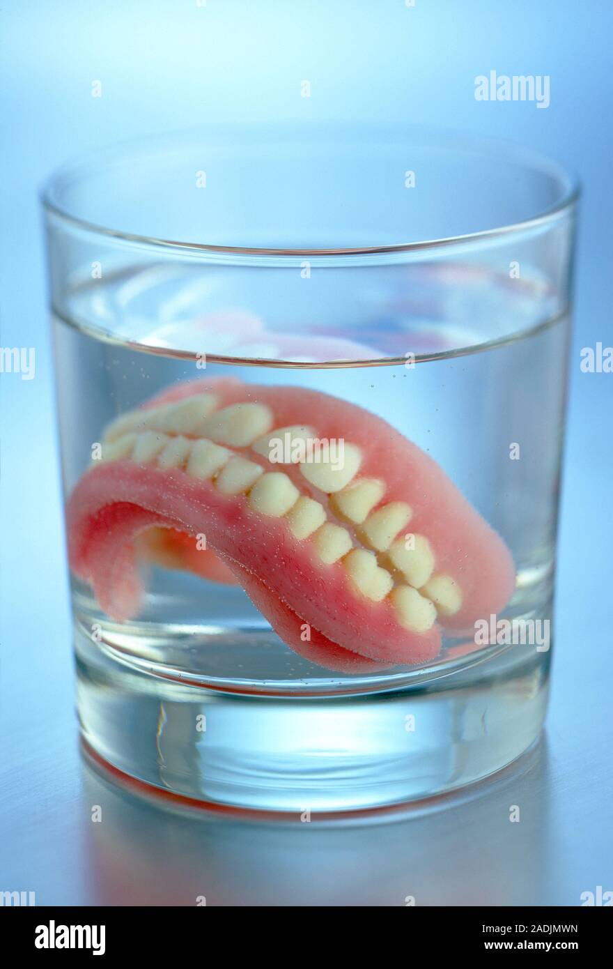 False teeth in a glass of water. These dentures are designed to fit an ...