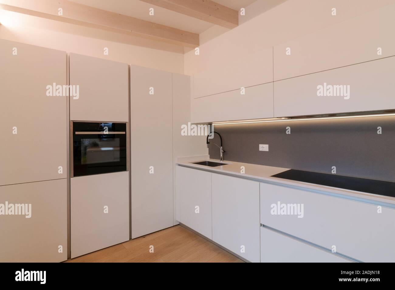 Modern and elegant kitchen interior with white cabinets, induction hob ...