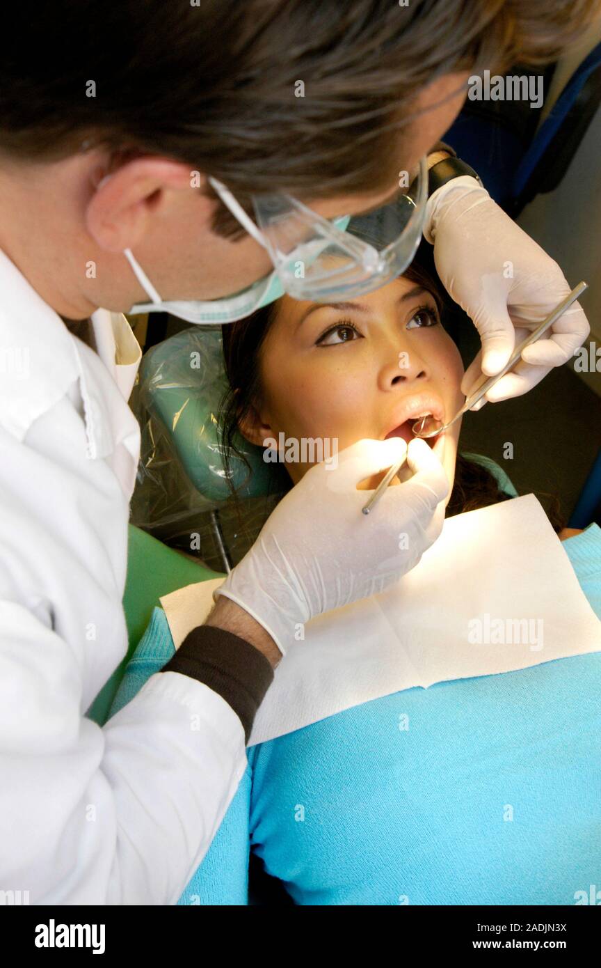 MODEL RELEASED. Plaque removal. Dentist scraping a female patient's ...