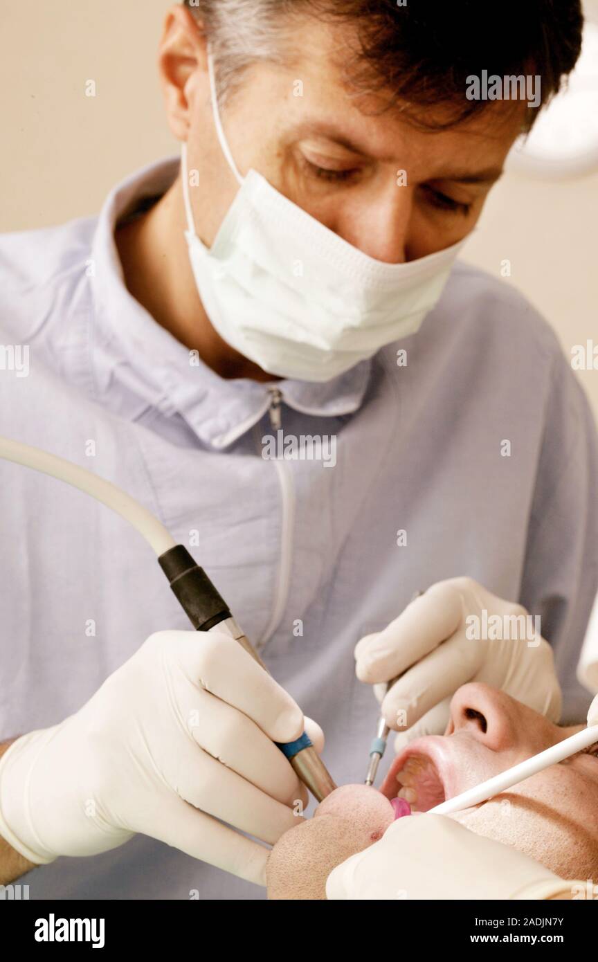 Dental treatment. Dentist using an electric tool during treatment of a ...