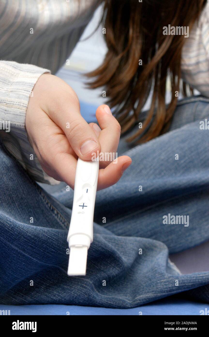 MODEL RELEASED. Home pregnancy testing. Young woman holding a home ...