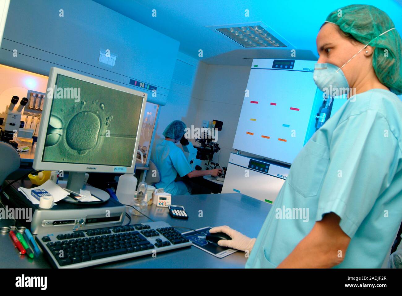 IVF treatment. Scientist (in background) using a light microscope and ...
