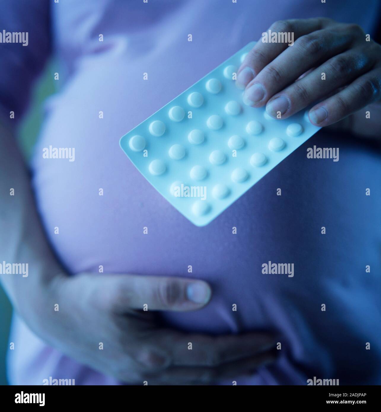 Folic acid in pregnancy. Pregnant woman holding a blister pack of folic ...