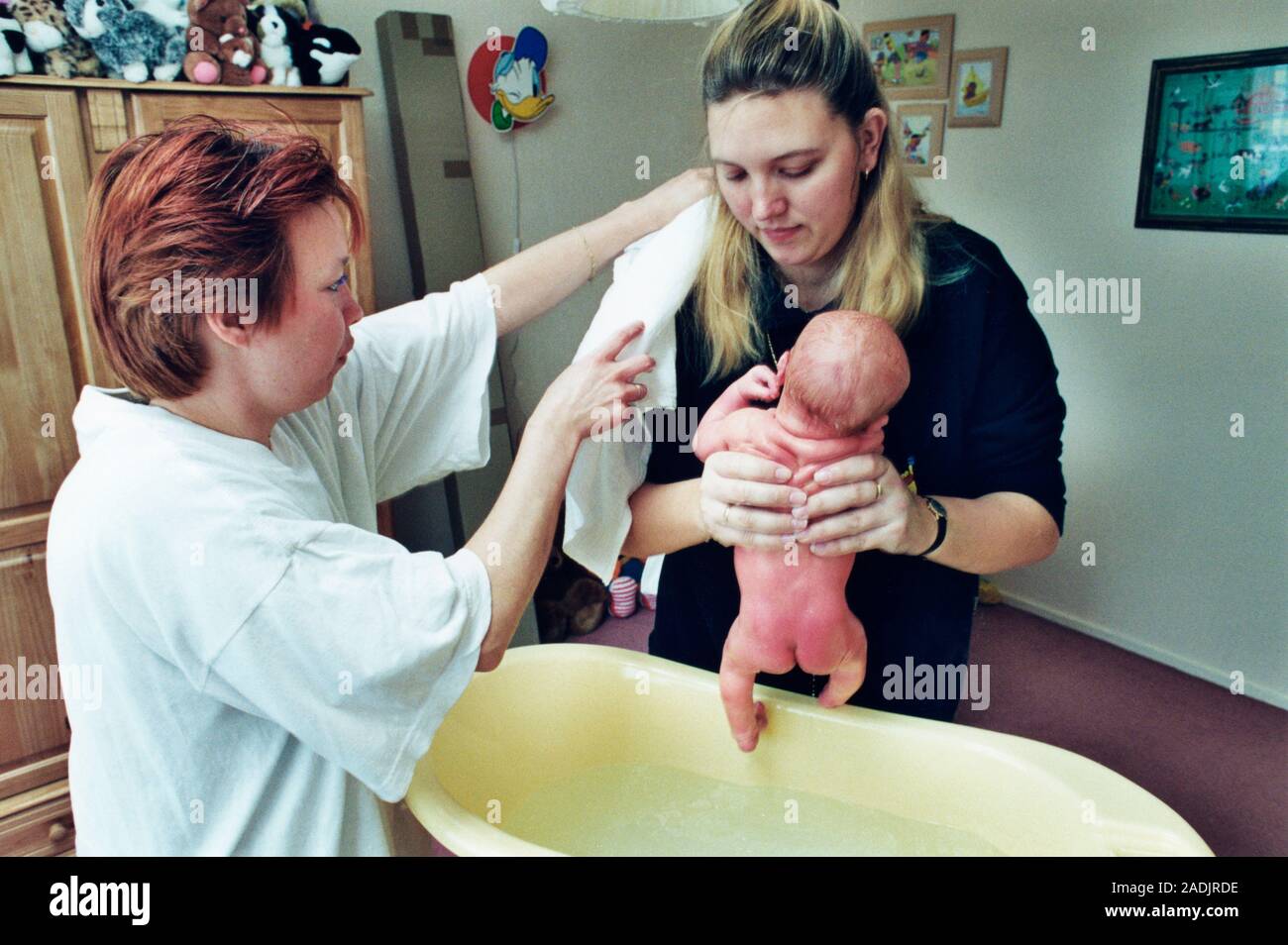Newborn baby boy being washed in a bath at home. Photographed in the ...