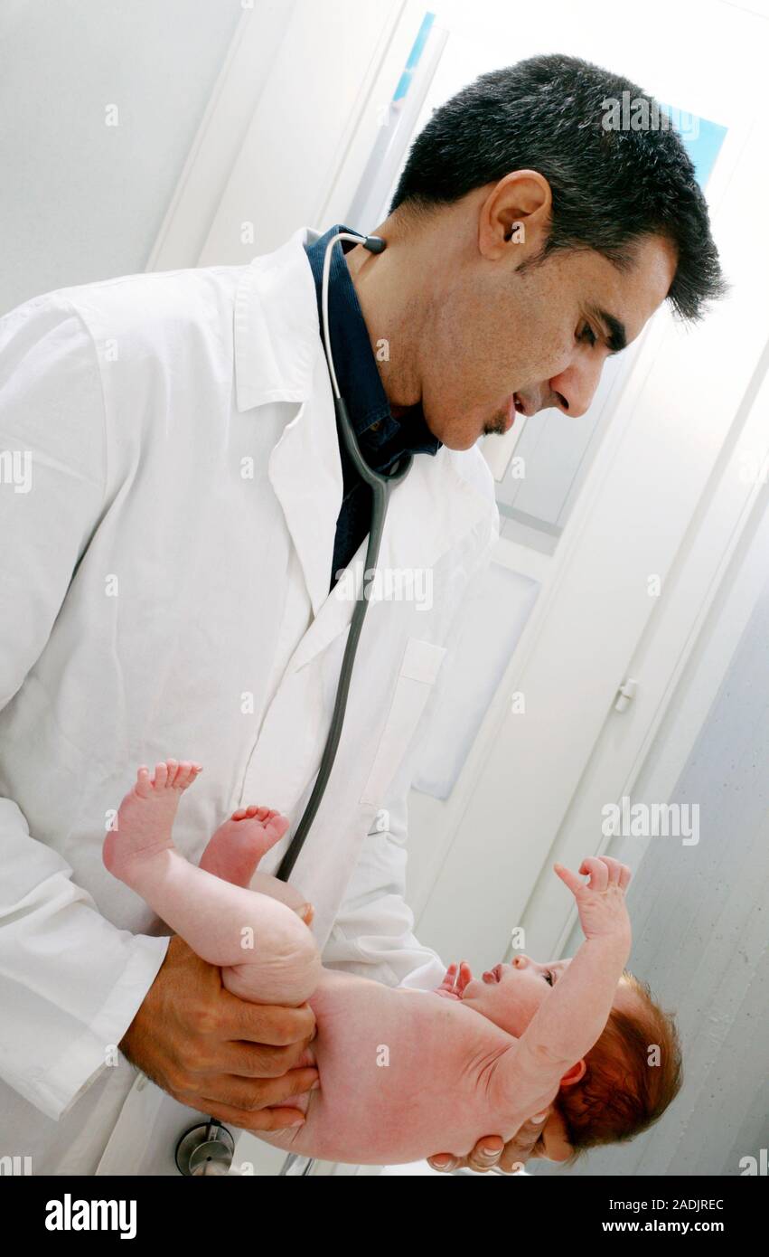Neonatal examination. Doctor carrying a newborn baby boy during a ...