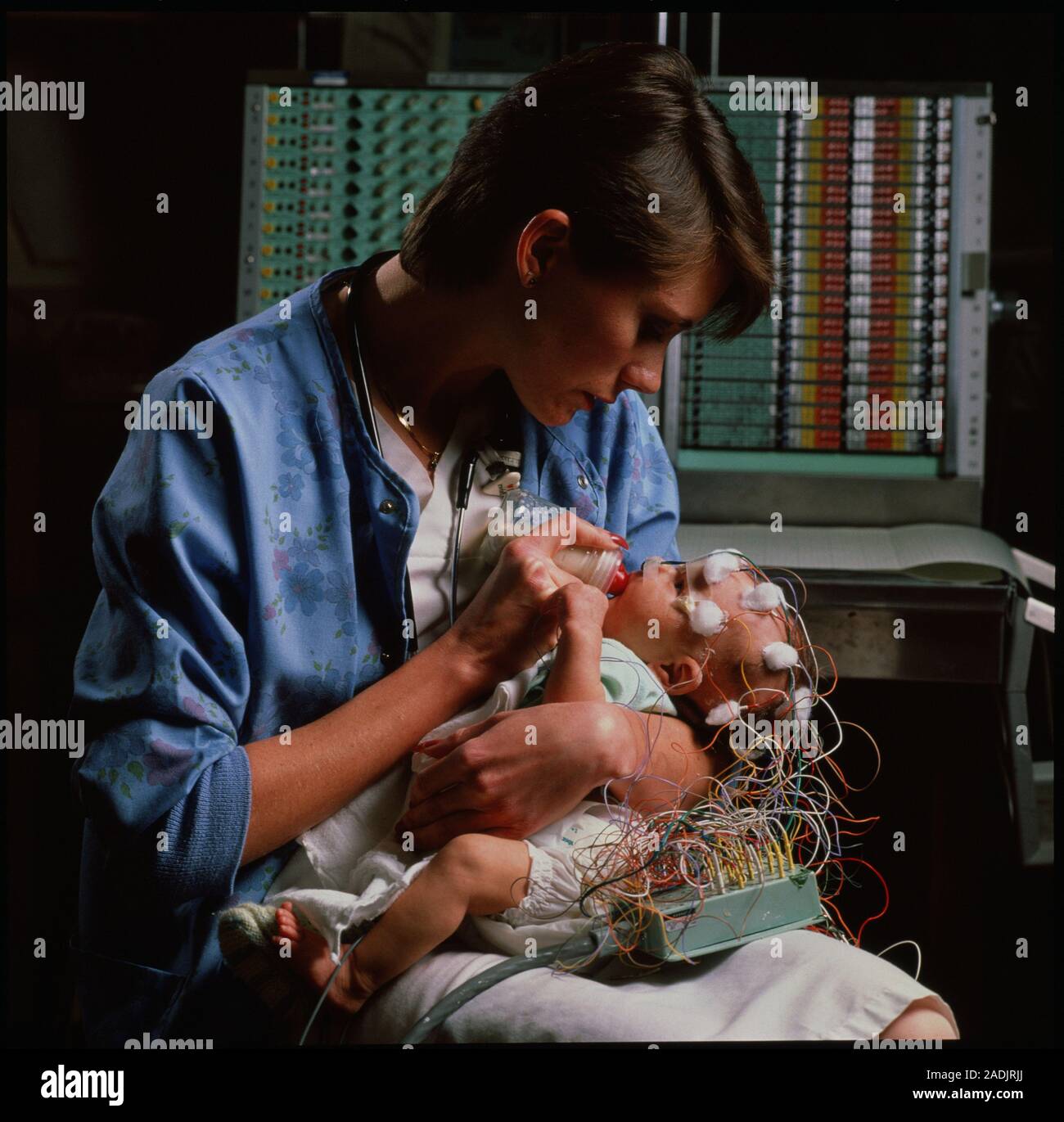 Nurse attending a neonatal (premature) infant whose head is covered ...