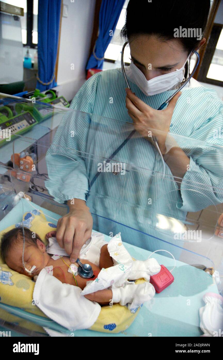 MODEL RELEASED. Premature baby. Doctor examining a premature baby with ...