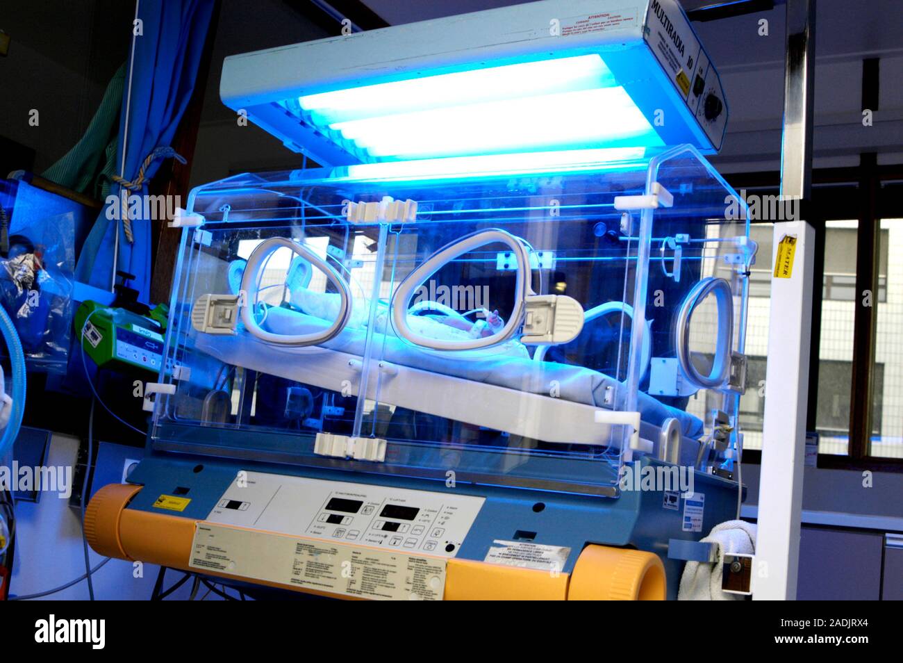 MODEL RELEASED. Phototherapy. Newborn baby in an incubator under a ...