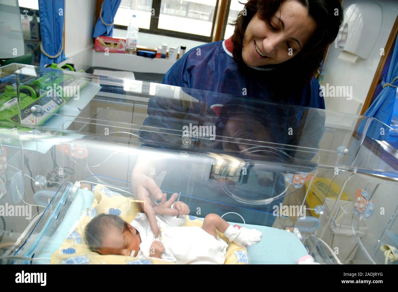Premature baby. Mother stroking her premature baby. Incubators provide ...