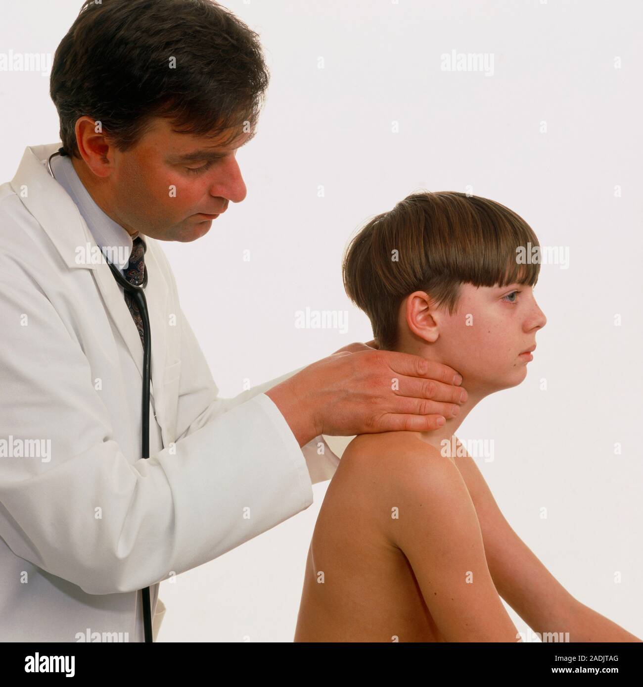 Neck examination. Teenage boy having his neck palpated by a general ...