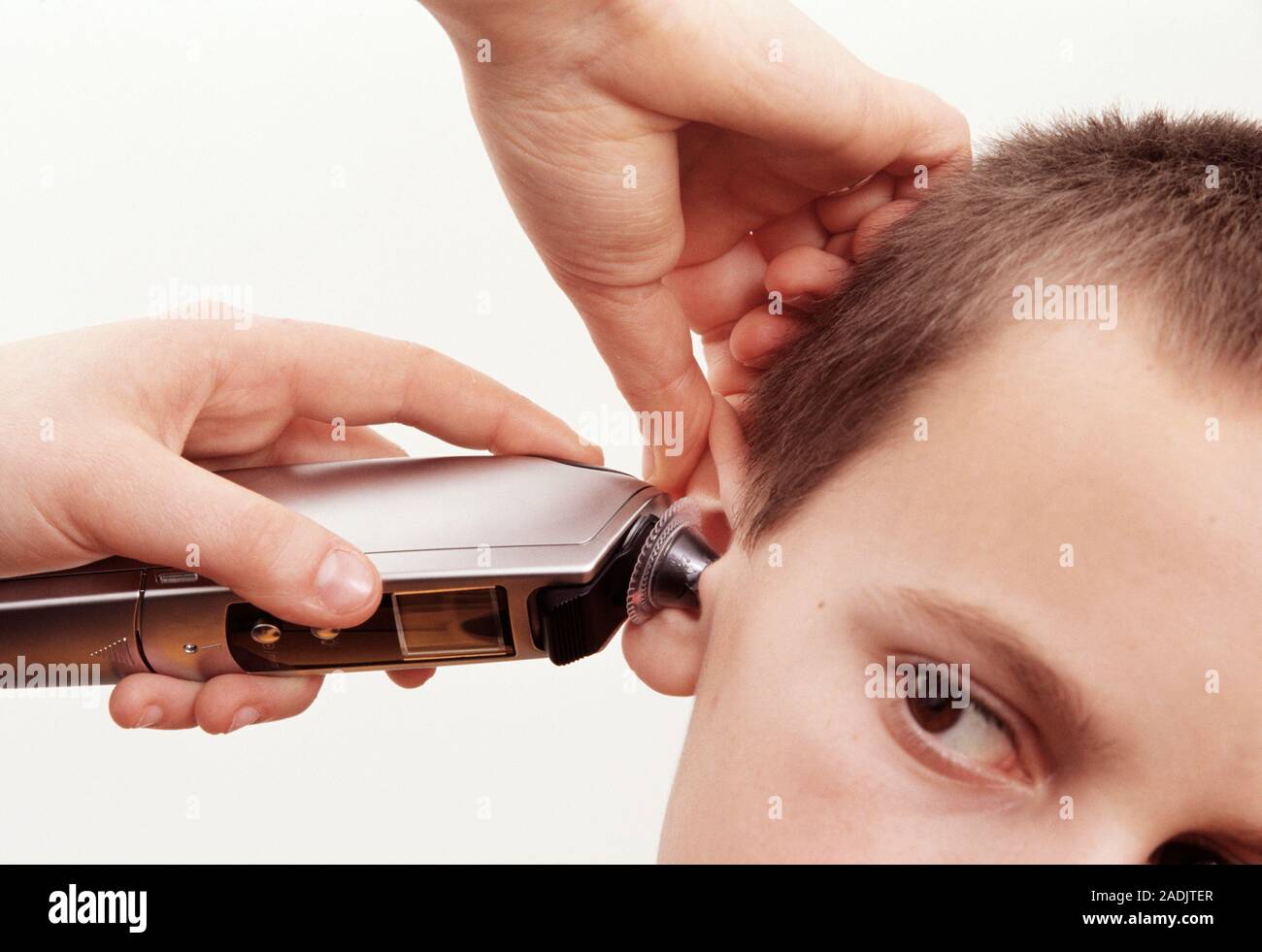 Digital tympanic thermometer, in the ear of a young boy. It is a modern ...