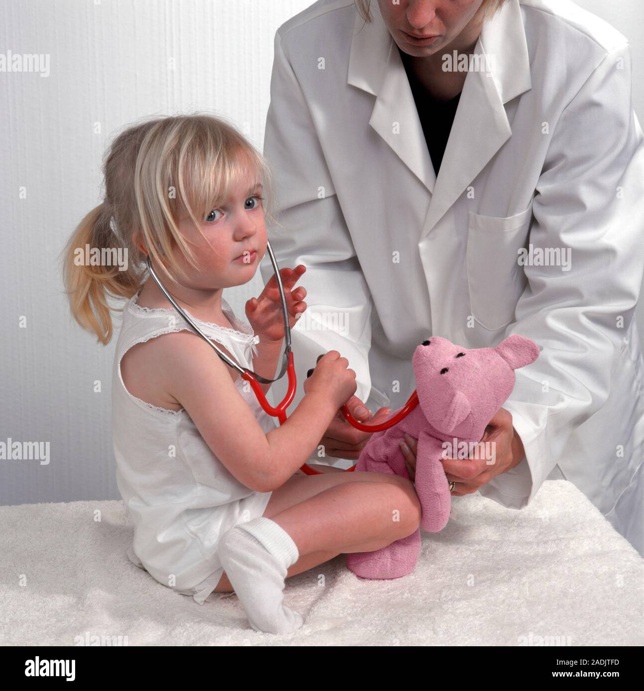 Medical examination. Paediatrician showing a girl how to use a ...