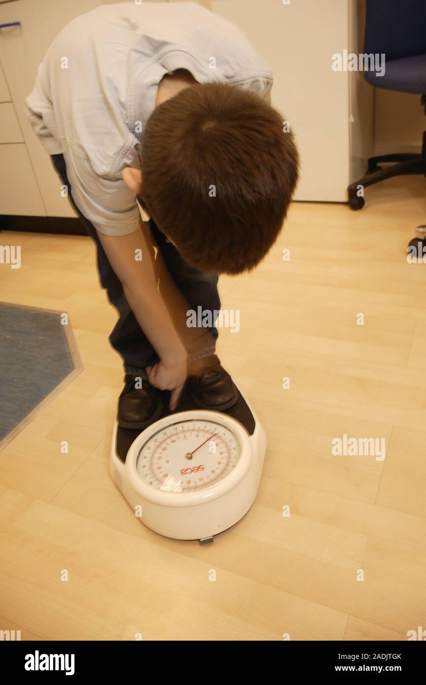 Weight measurement. Boy pointing at scales showing his weight. His ...