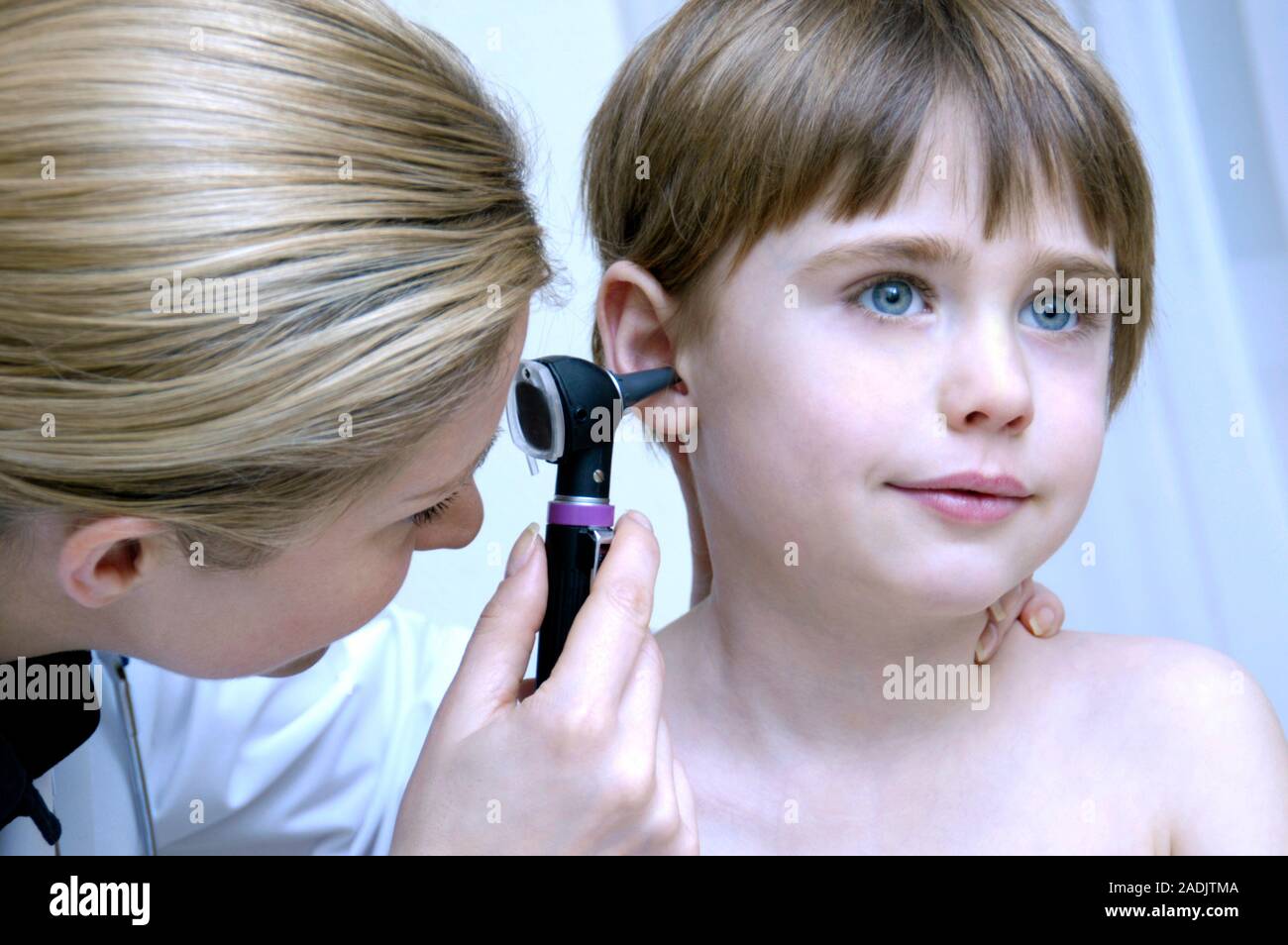 MODEL RELEASED. Ear examination. Paediatrician using an otoscope to ...