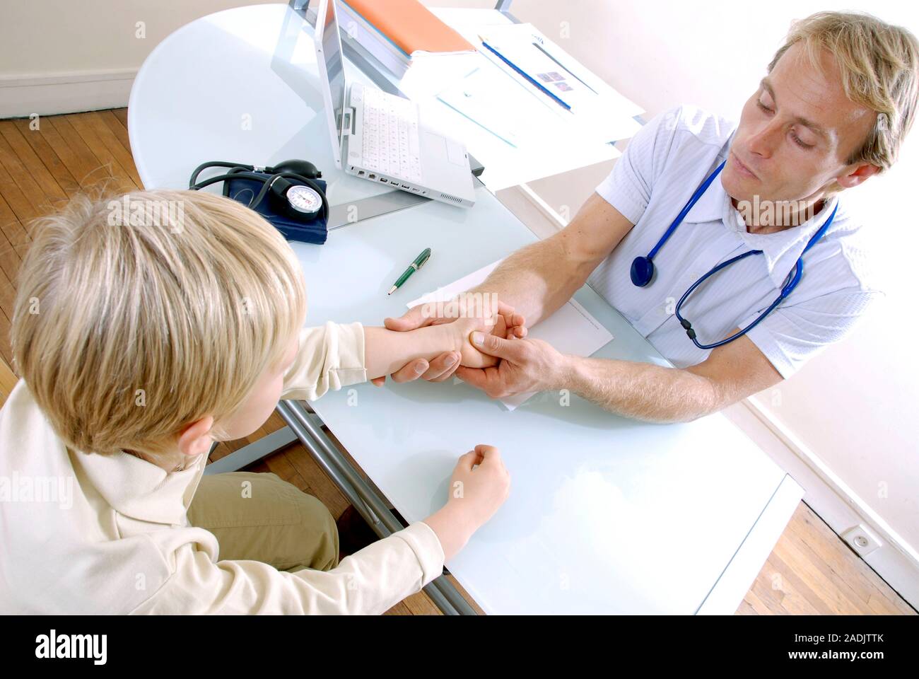 Paediatric examination. Paediatrician examining a young boy's hand ...