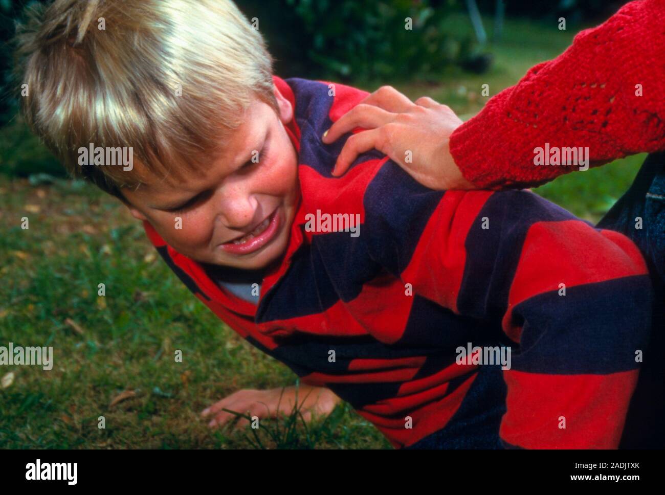 Fighting children. A young boy with an angry look on his face is pushed ...