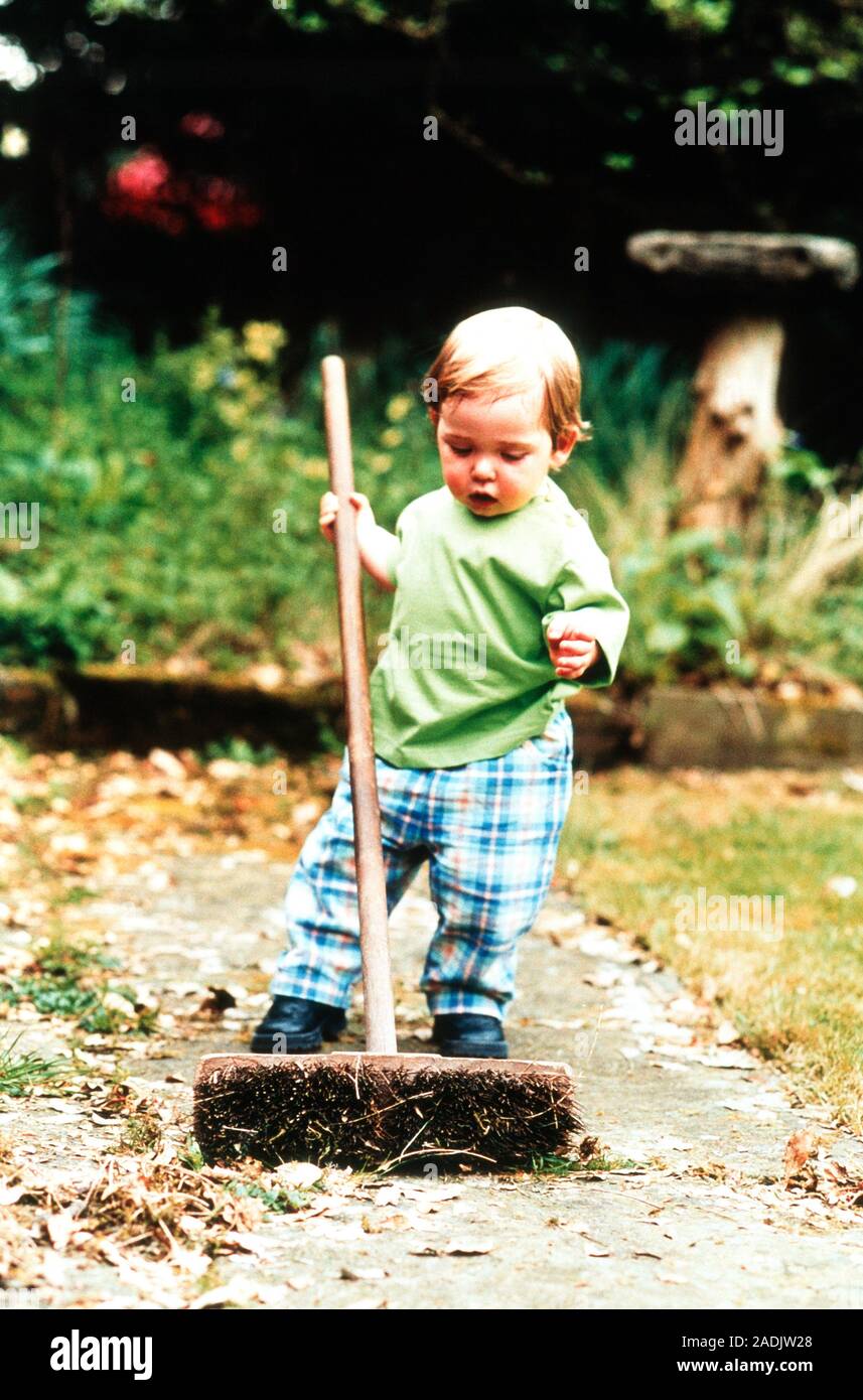 Boy using broom. Young boy (approximately 18 months old) trying to ...