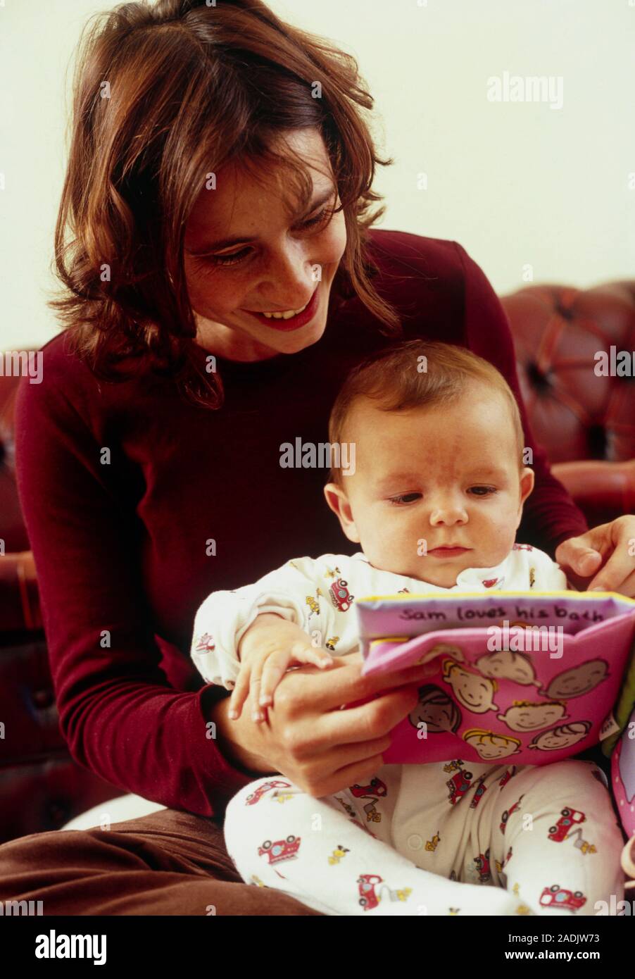 Reading to baby. Smiling mother reads to her six-month-old baby boy ...