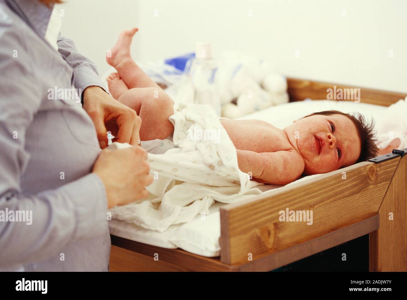Baby girl having her nappy changed by her mother. She is two months old ...