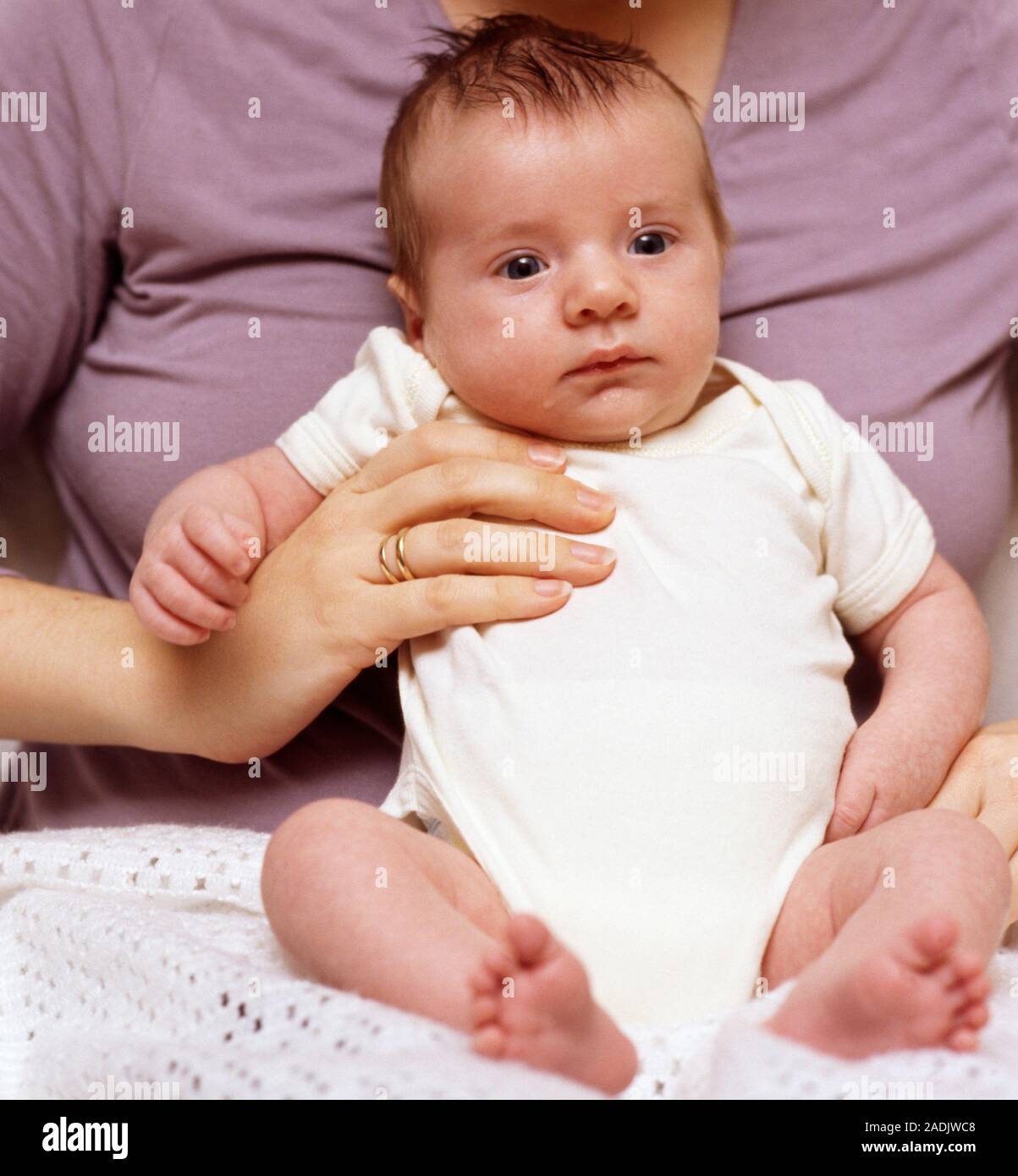 Baby boy. 1-month-old baby boy being supported by his mother's hand. A ...