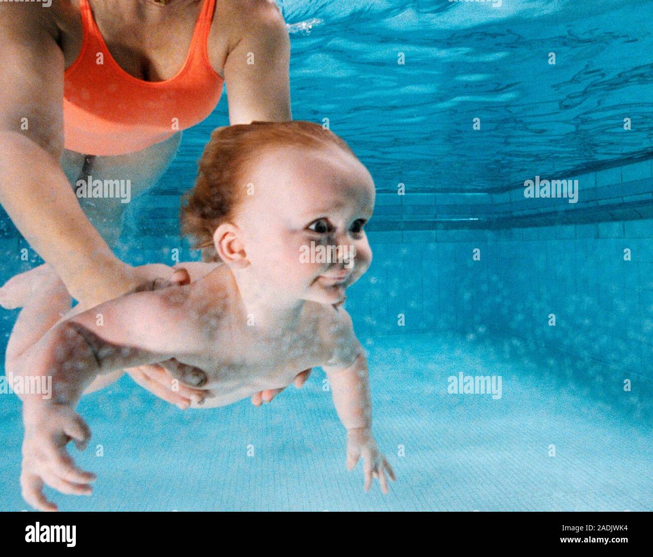 Baby swimming underwater while being supported by its mother Stock ...